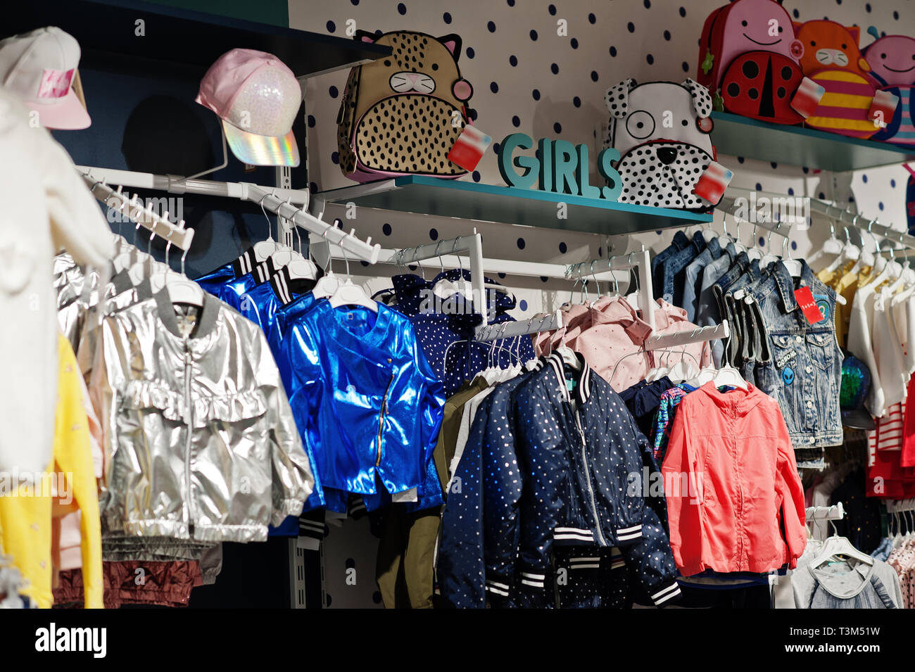 Children's bright clothes hang on the display in the baby clothing ...