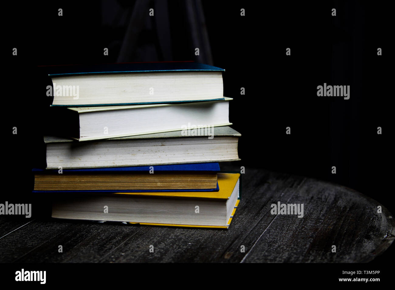 Stack of old books on round wood table with reading light during night ...