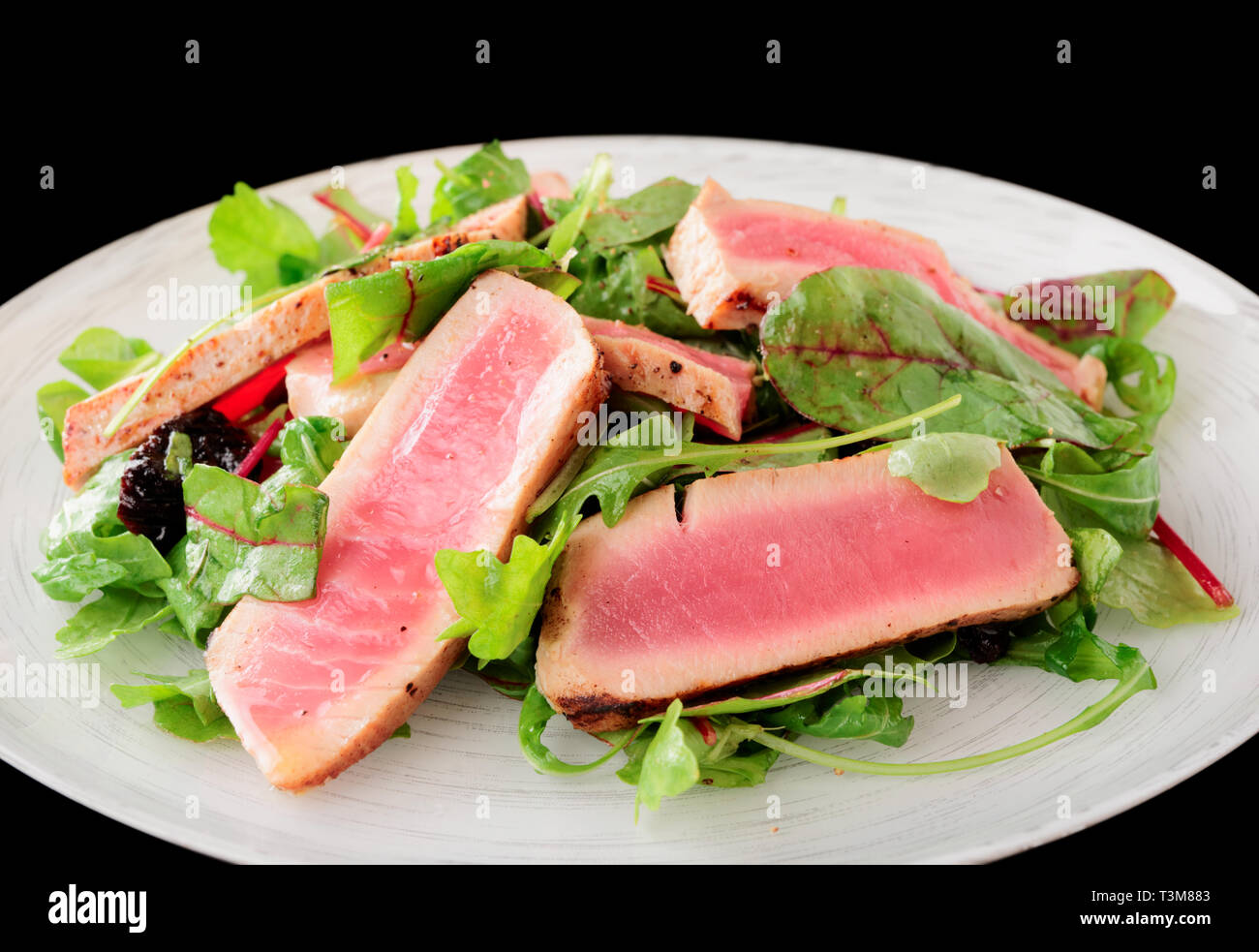 Appetizer with rare fried tuna in plate isolated on black background ...