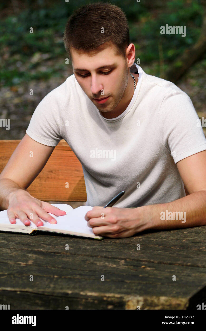 Guy and student takes notes in notebook, learning and writes thoughts ...