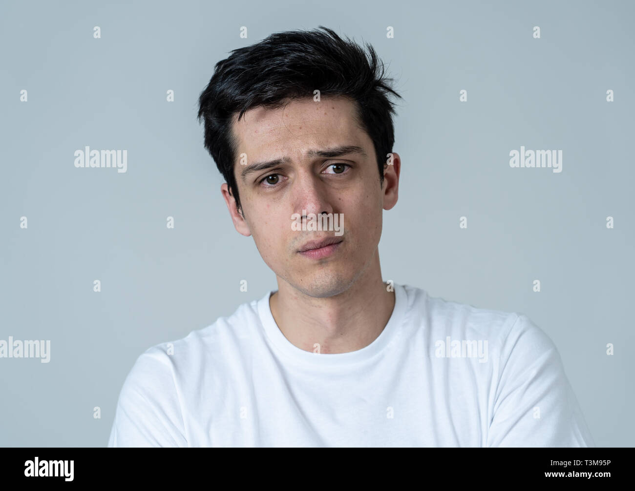 Close up of a young sad man, serious and concerned, looking worried and ...