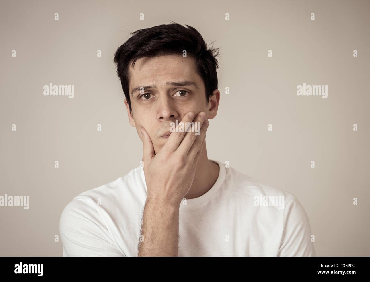 Close up of a young sad man, serious and concerned, looking worried and ...