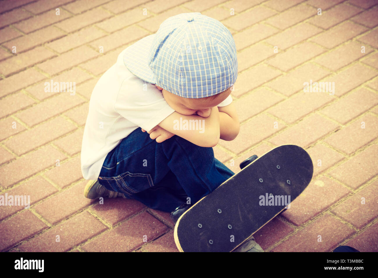 Lonely sad child boy with skateboard. Depressed sullen kid. Loneliness ...