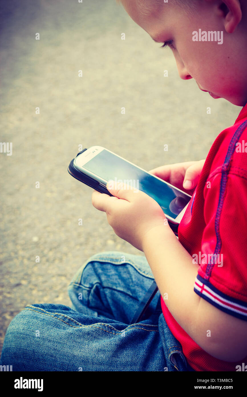 Little boy child kid playing games on smartphone mobile phone outdoor ...