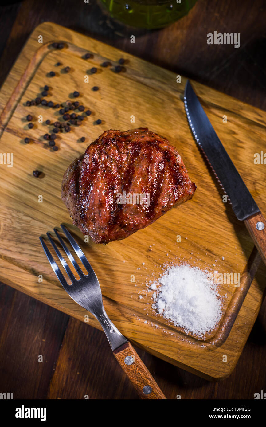 Grilled pork rib chop steak in a clay plate with oil, mustard, salt and ...