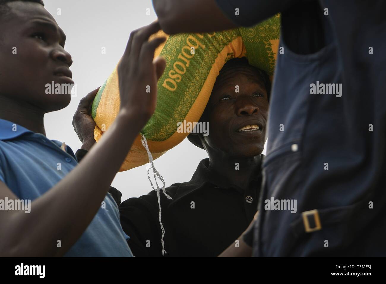 Local volunteers assist in unloading food aid from a helicopter in the ...