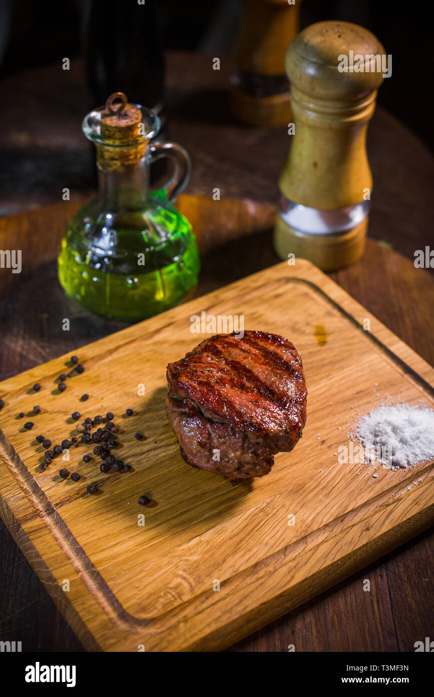 Grilled pork rib chop steak in a clay plate with oil, mustard, salt and ...