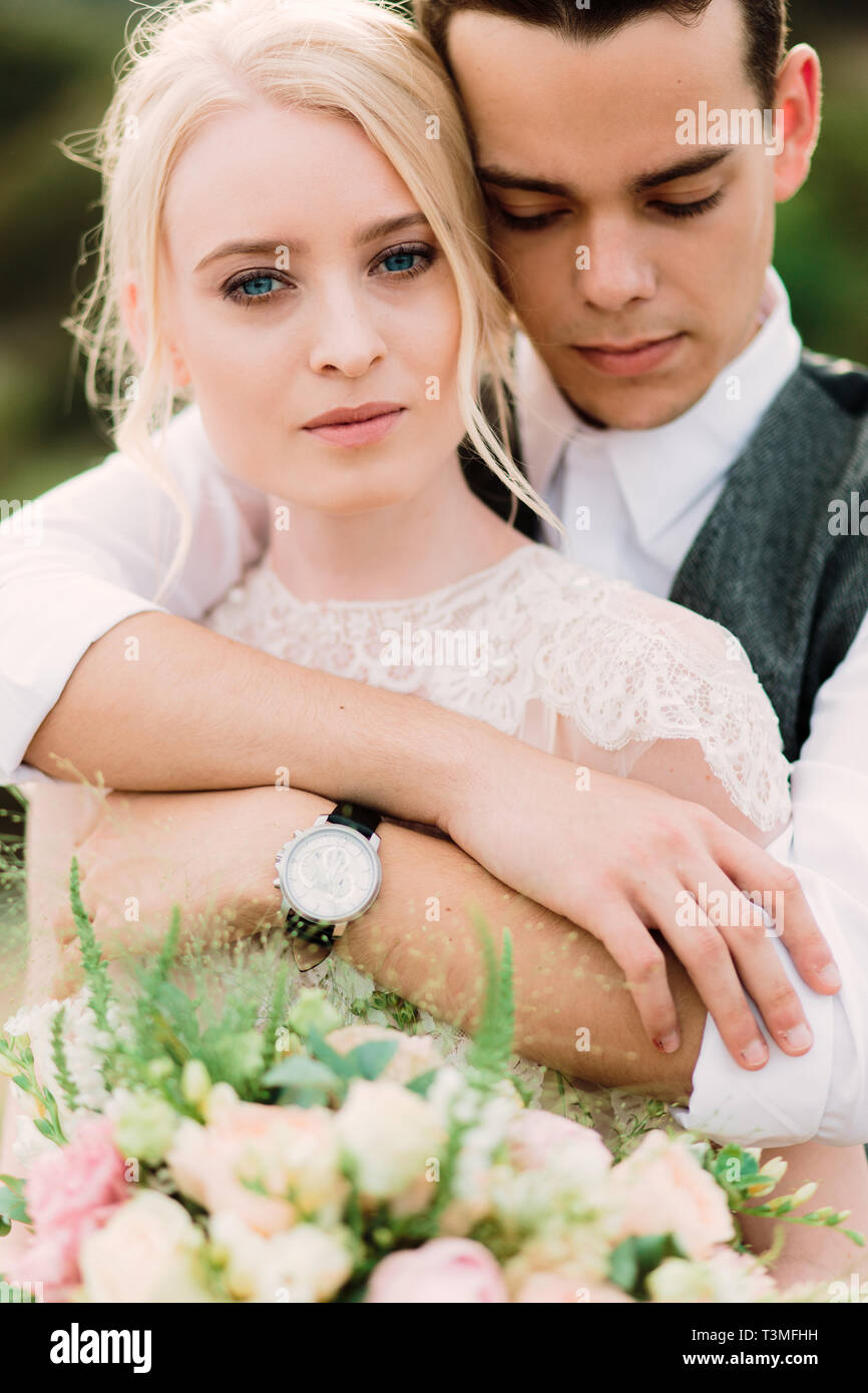 Beautiful bride and groom hug each other tender standing on the golden ...