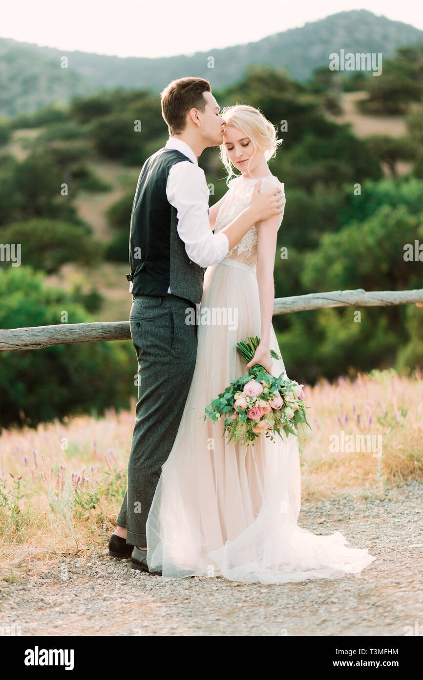 Beautiful bride and groom hug each other tender standing on the golden ...