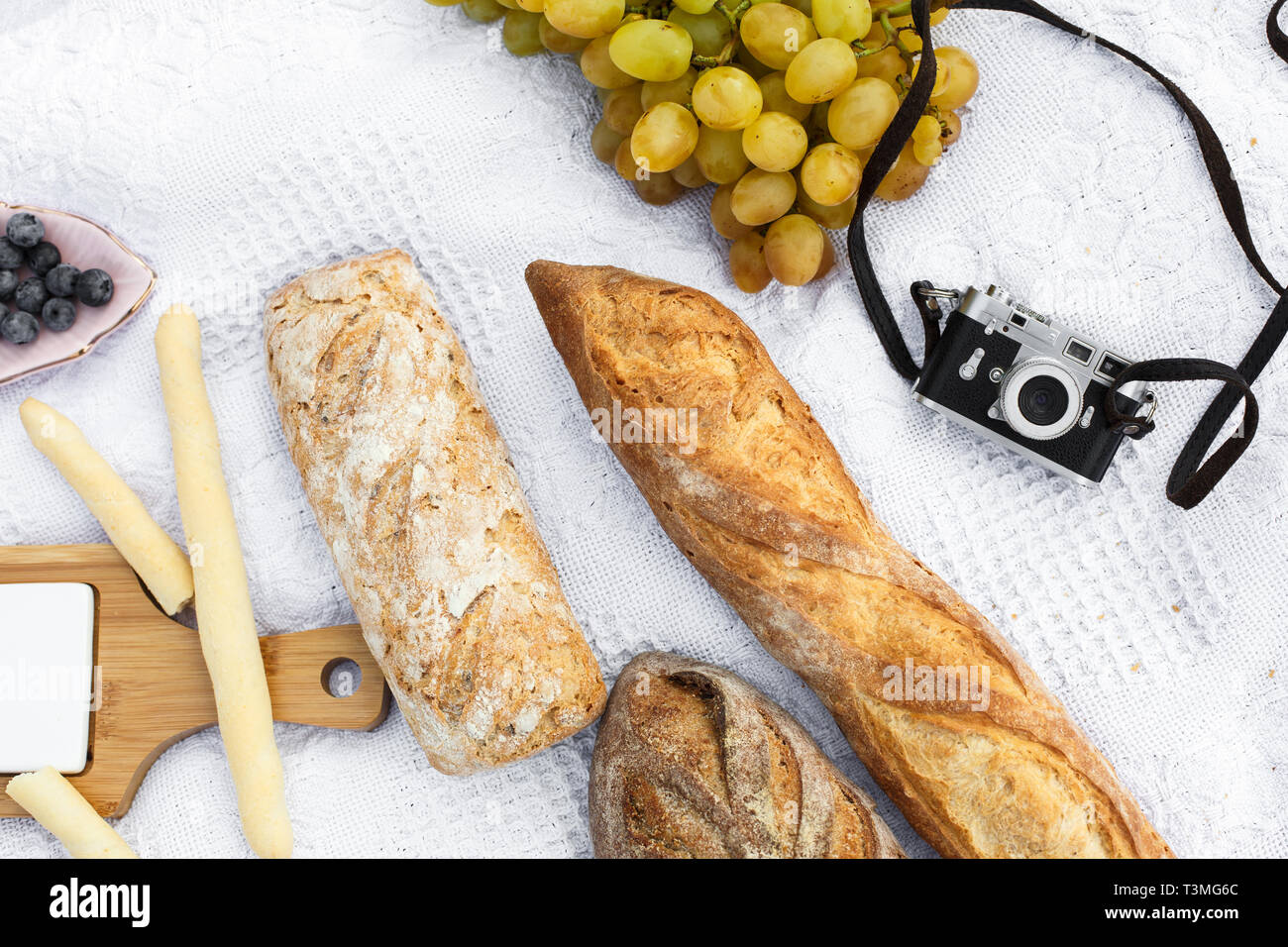 Food lay out on picnic blanket. fresh baked bread, grapes, olives and ...