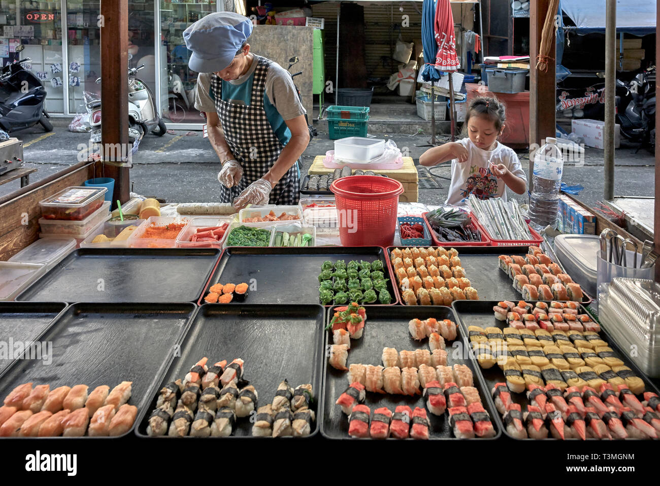 Thailand street food stall selling sushi and with child helping mother ...