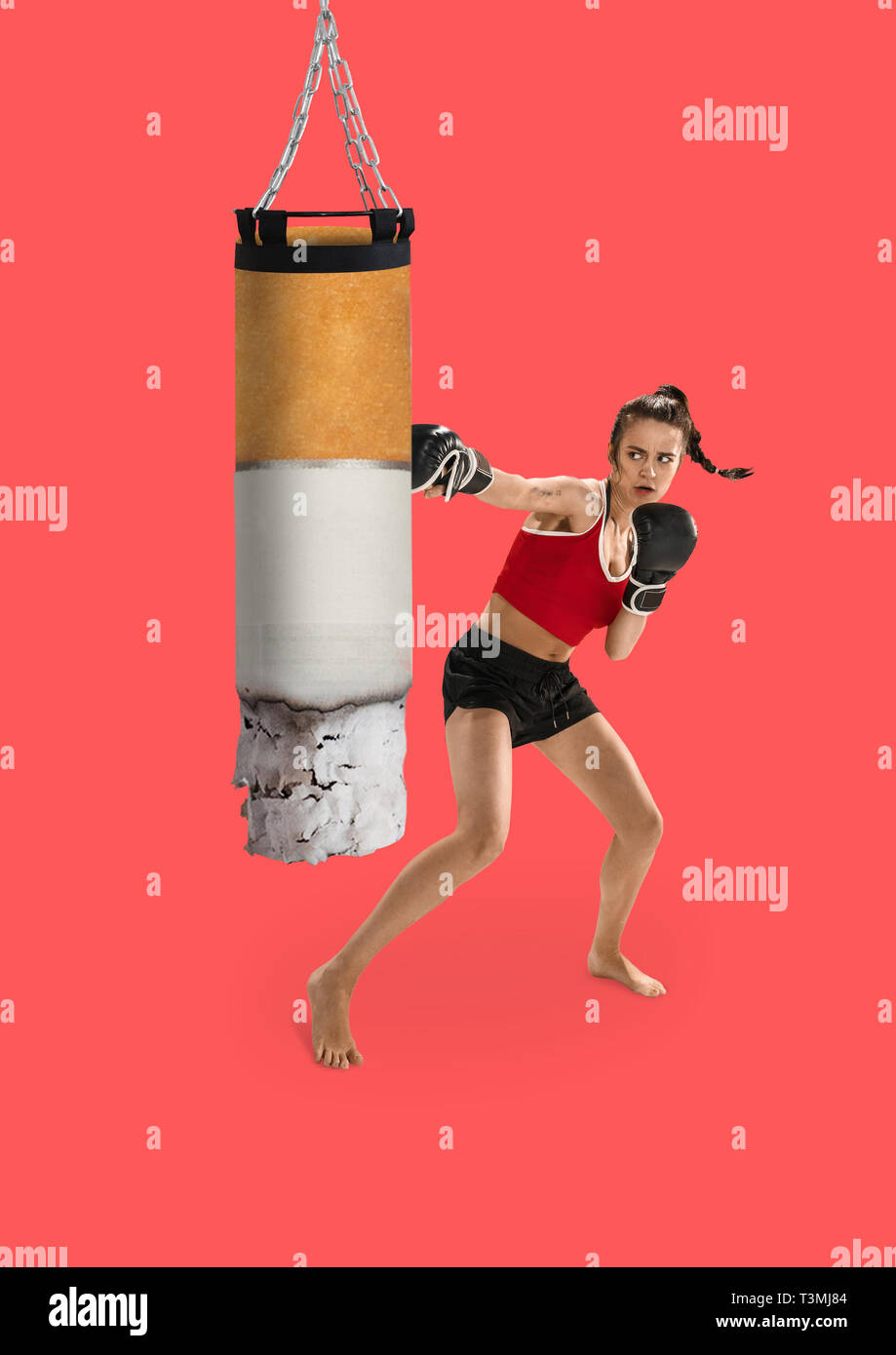 Last hit to the habit. Woman boxing cigarette as a punching bag against ...