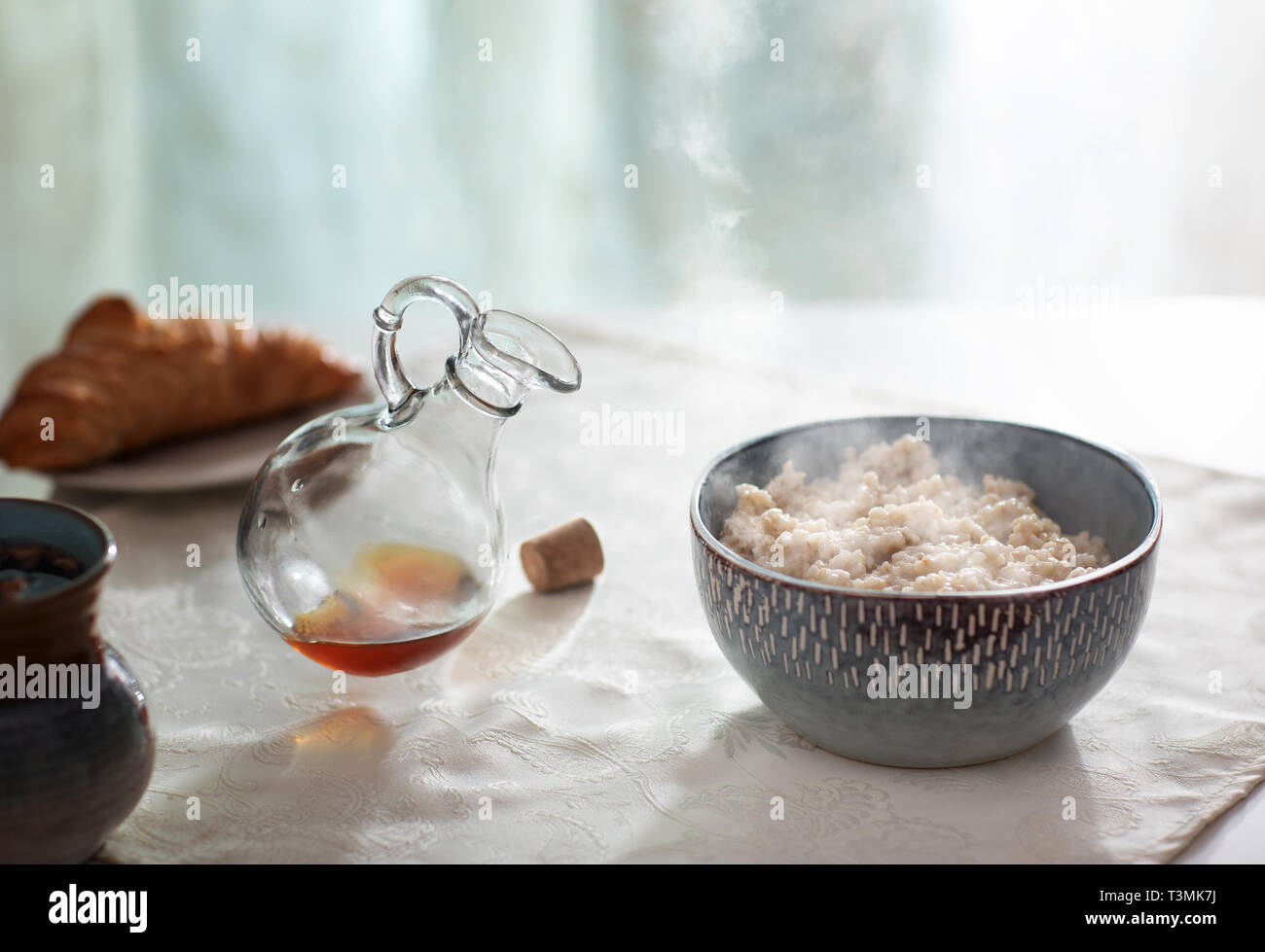 Healthy vegan breakfast: hot steaming oatmeal with tea and croissant ...