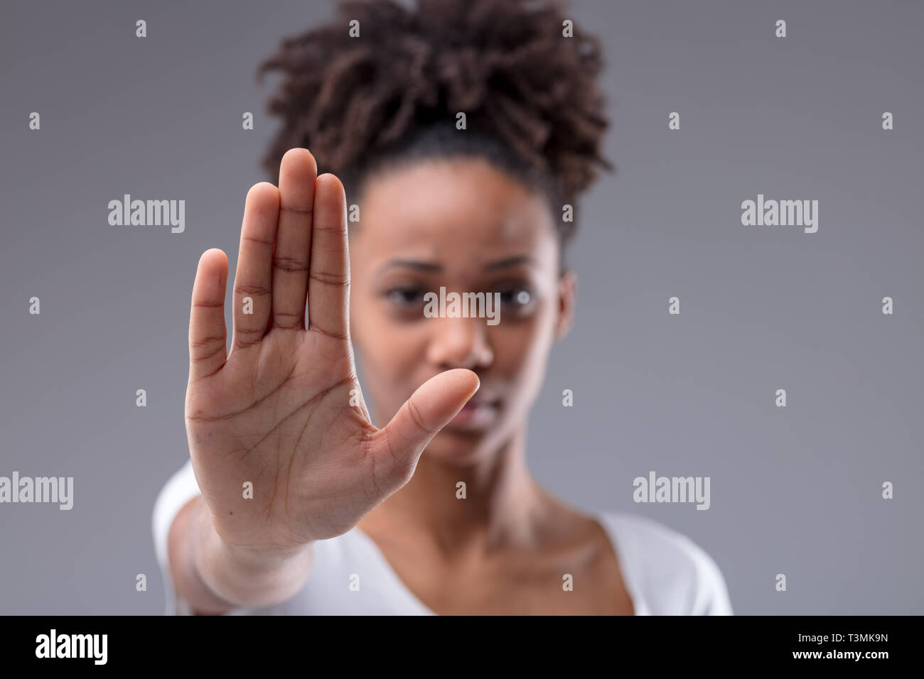 Attractive young African woman giving a halt or stop gesture with focus ...