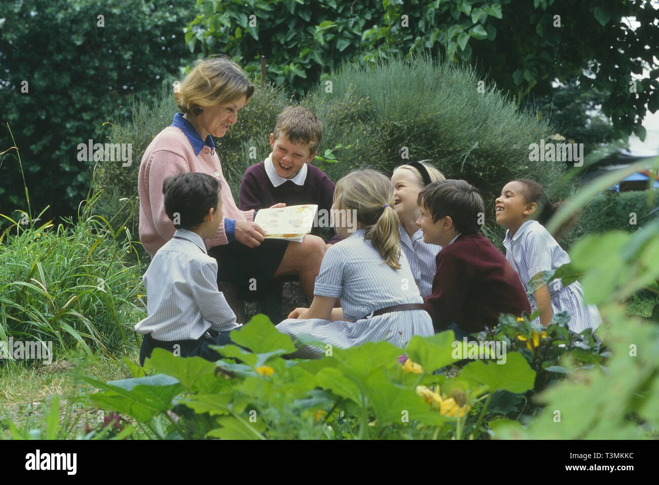 A small class of children listening to a story read by their teacher ...
