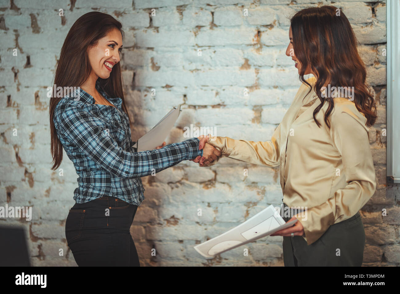 Two business women are shaking hands with each other after good deal in ...