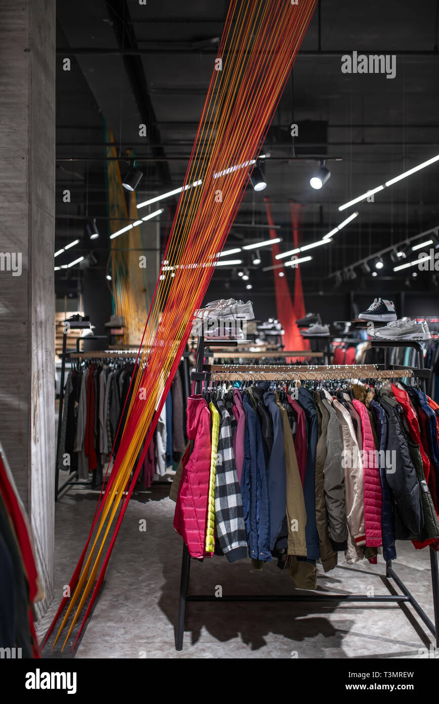 Modern clothes shop with large selection of different wear and shoes ...