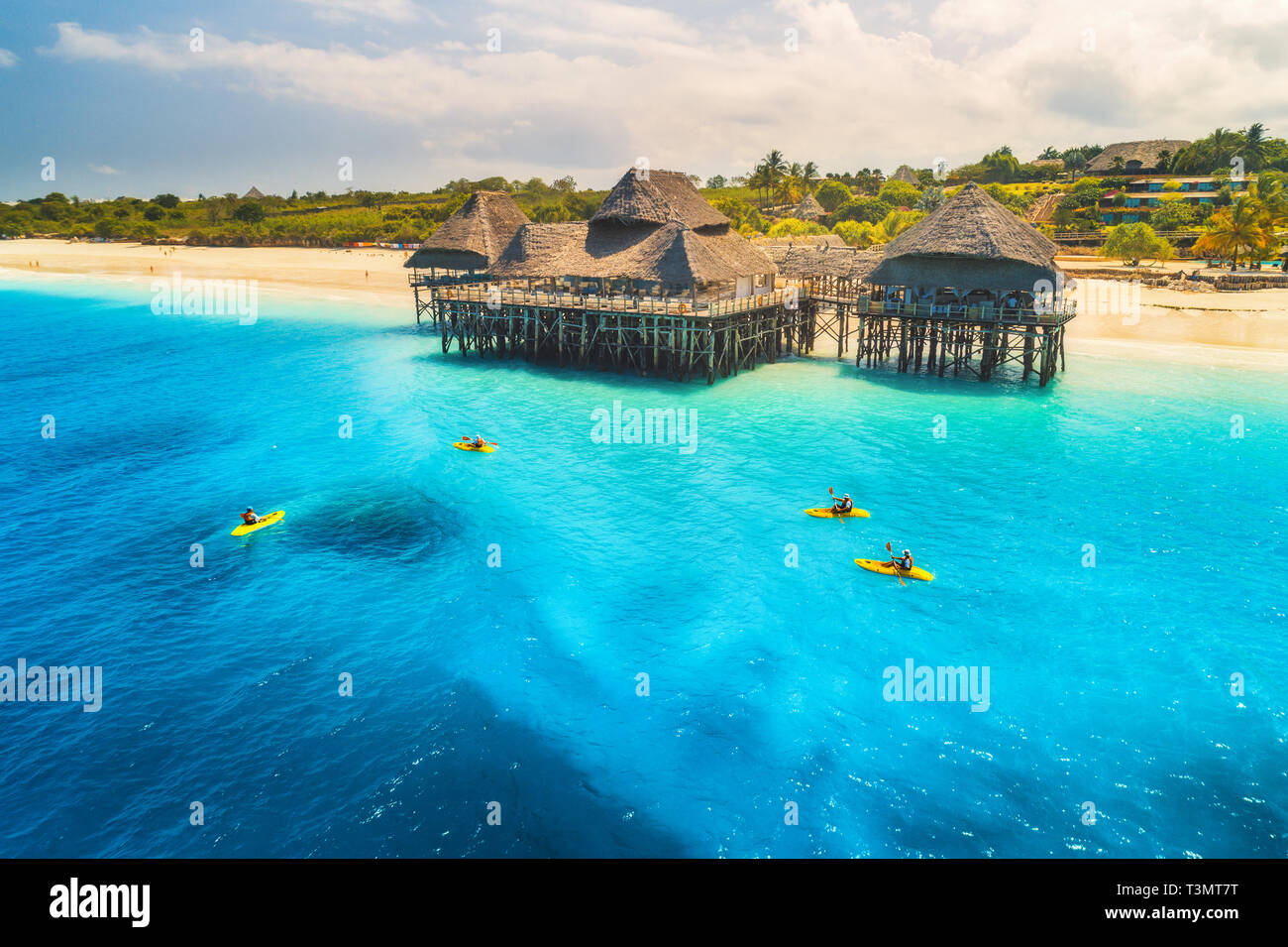 Aerial view of beautiful hotel and people in kayaks at sunset in summer ...
