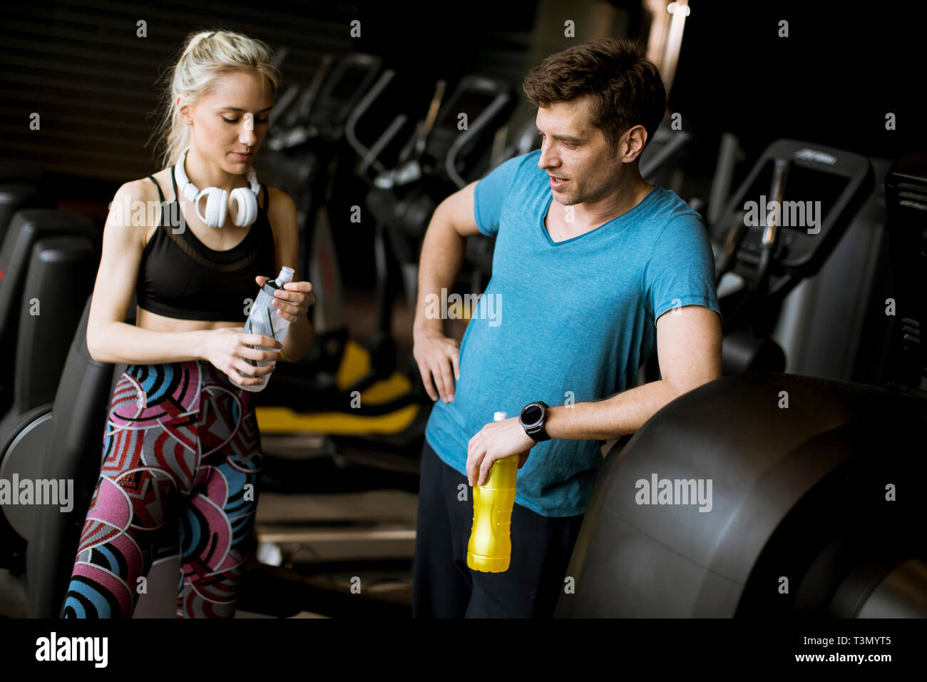 Young woman and personal male trainer rest in the gym after workout ...