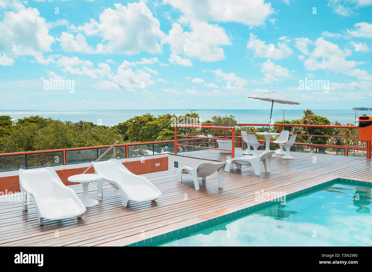 Hotel pool near the beach with the sea on background. Sun chairs and ...