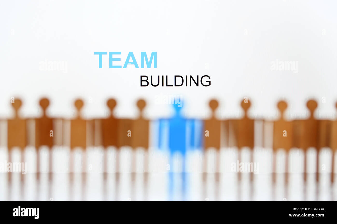 Team building sign above line of toy human figures Stock Photo - Alamy