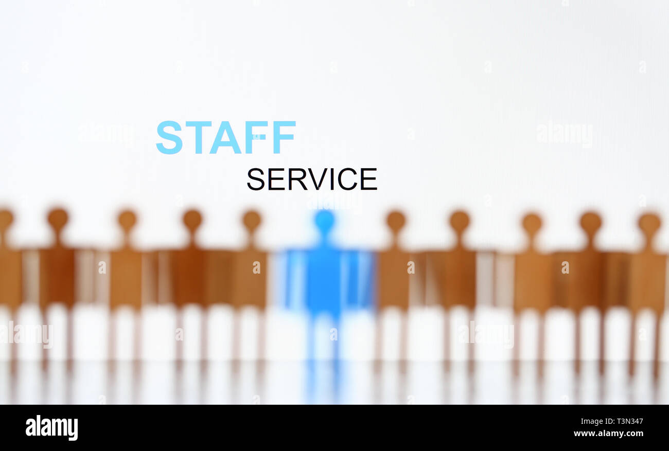 Staff service sign above line of toy human figures Stock Photo - Alamy