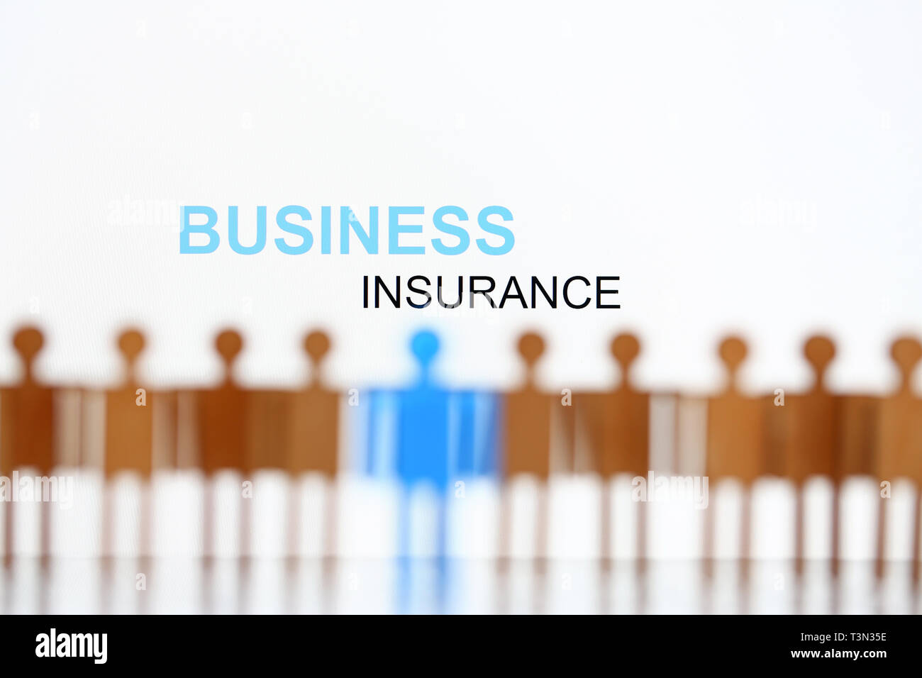 Business insurance sign above line of toy human figures Stock Photo - Alamy