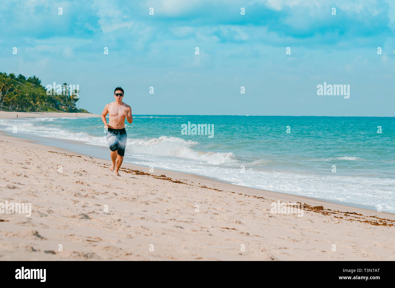 Man running on the beach during summer. Doing cardio exercise on the ...