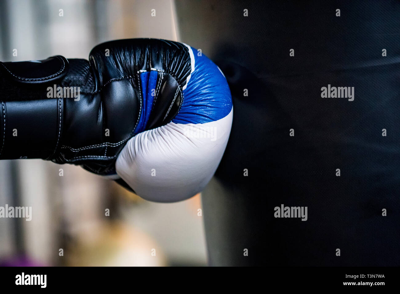 Boxing concept. Hand of boxer in glove hits black sandbag c Stock Photo ...