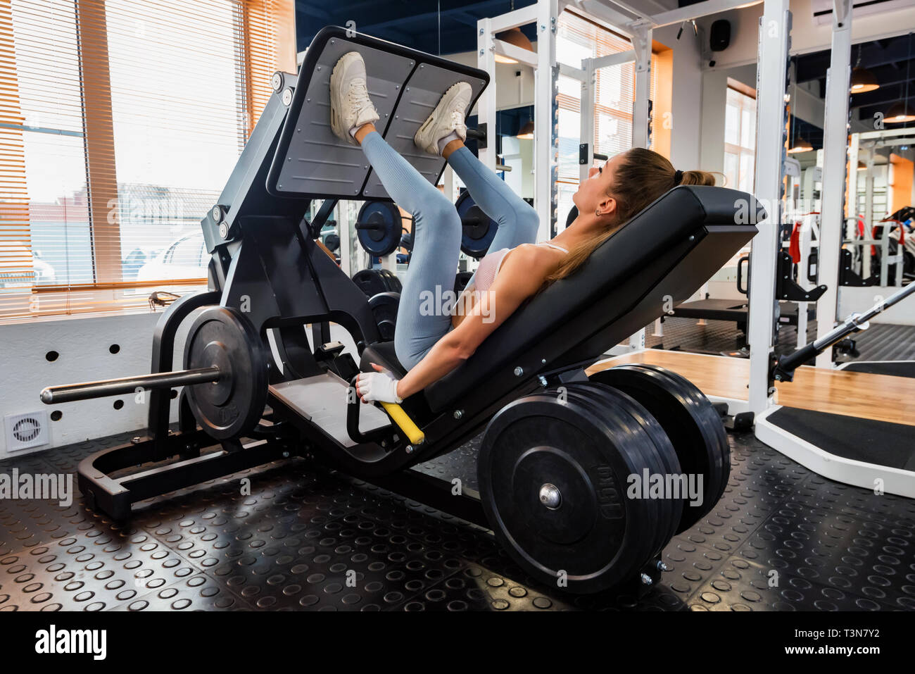 Strong young sportswoman doing leg exercises on gym machine Stock Photo ...