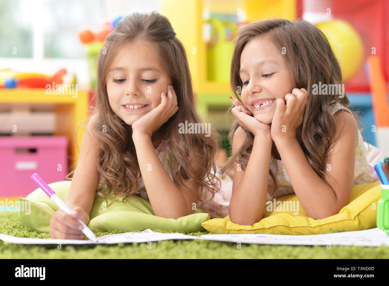 Two cute little girls drawing together at home Stock Photo - Alamy