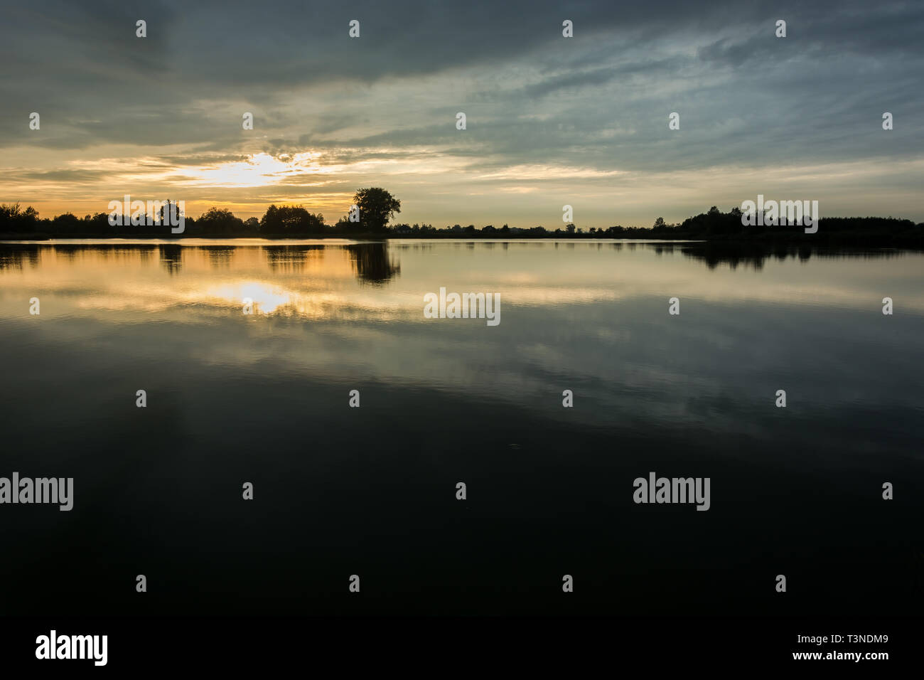 Dark clouds during sunset over a calm lake - evening view Stock Photo ...