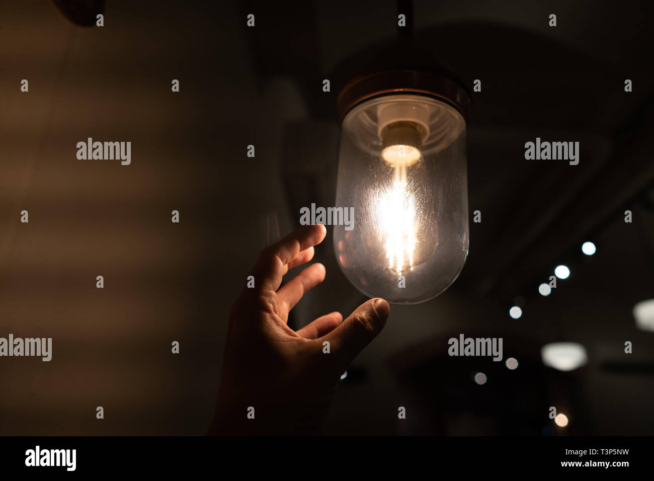 Hand reaching for a vintage light bulb Stock Photo - Alamy