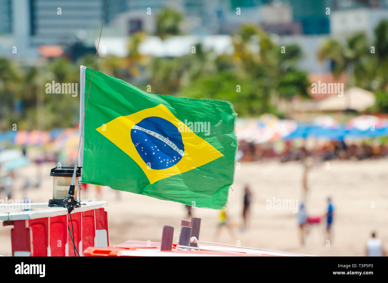 Brazilian flag swinging and a touristic beach on background. Touristic ...