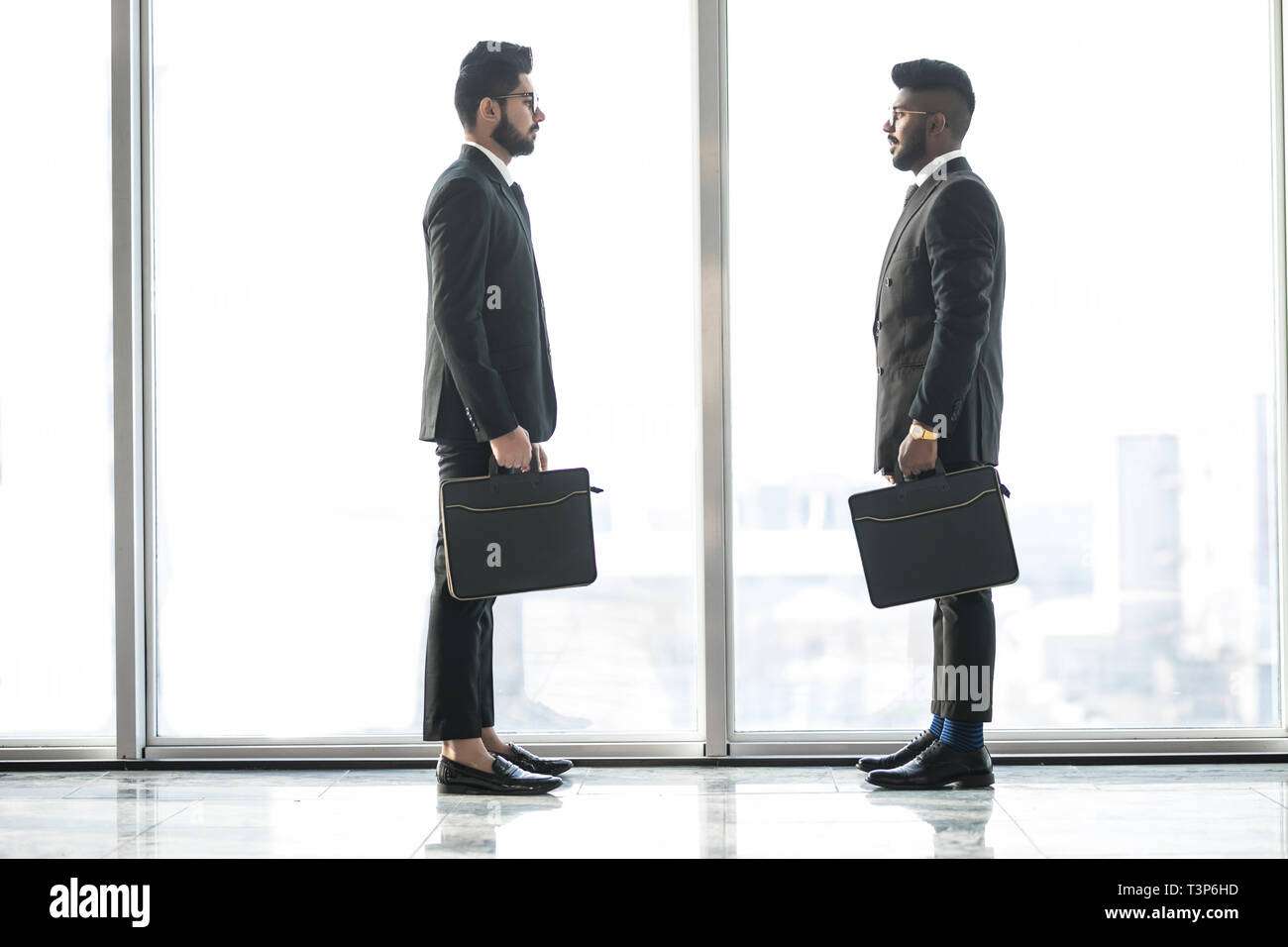 Two businessmen deep in discussion together while standing in an office ...