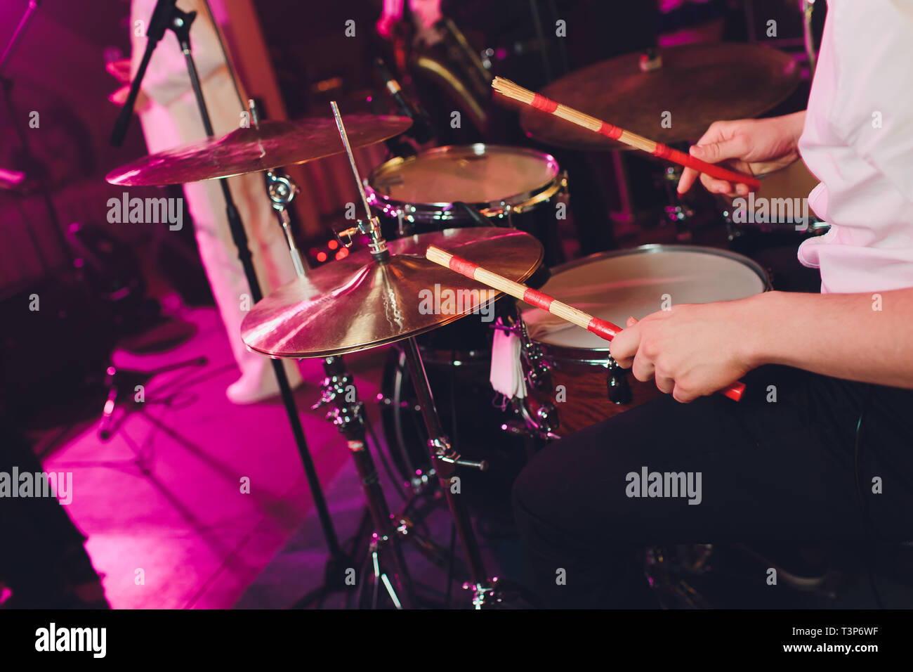 Drummer with a drumsticks in his hands playing on drum set on stage on ...