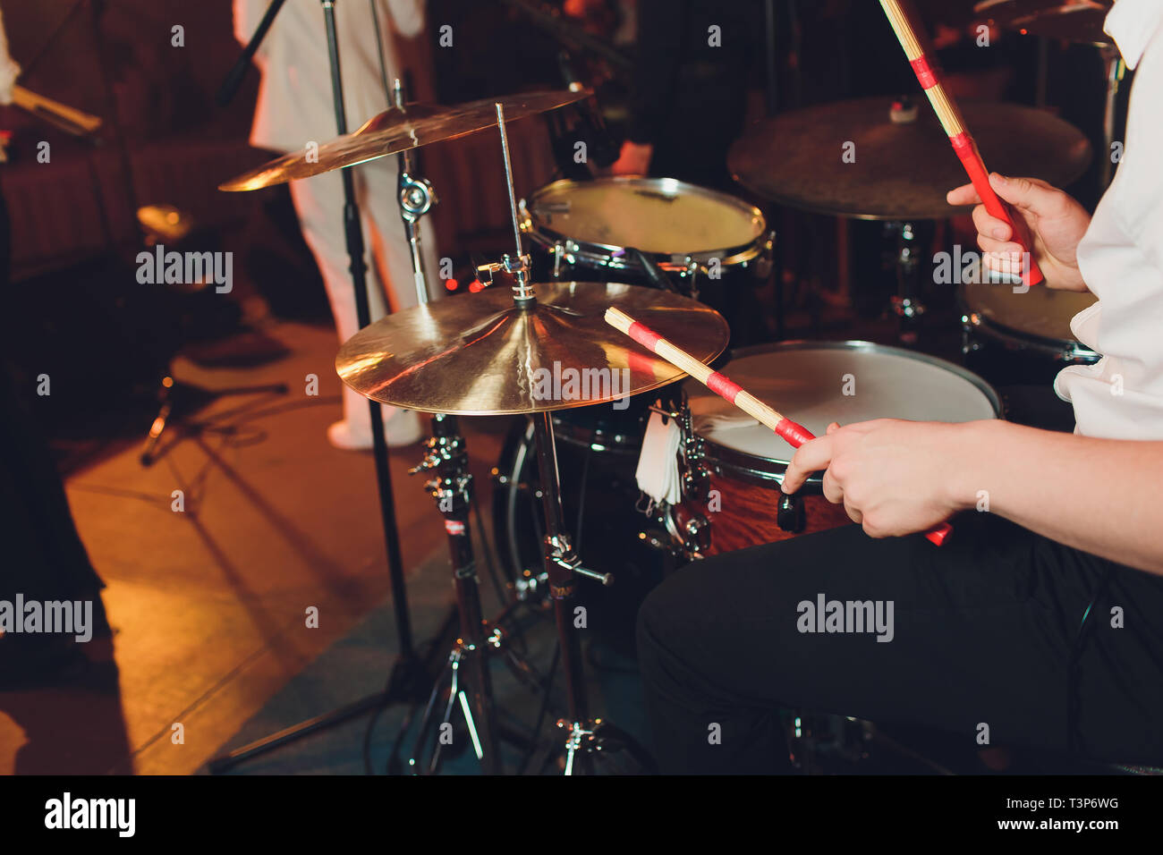 Drummer with a drumsticks in his hands playing on drum set on stage on ...