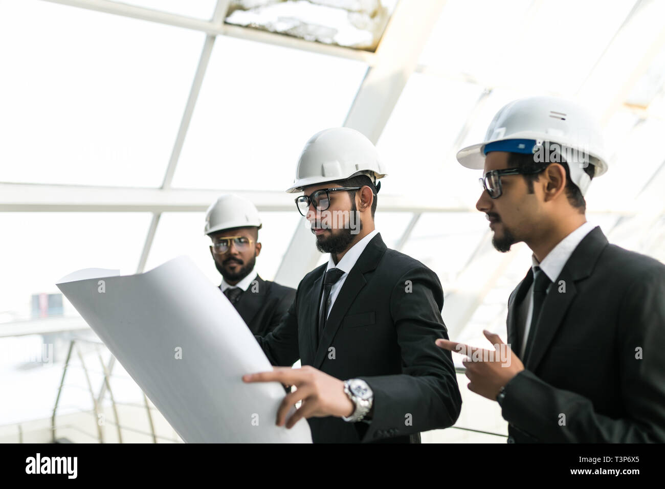 Qualified young architects are standing and discussing plan of building ...