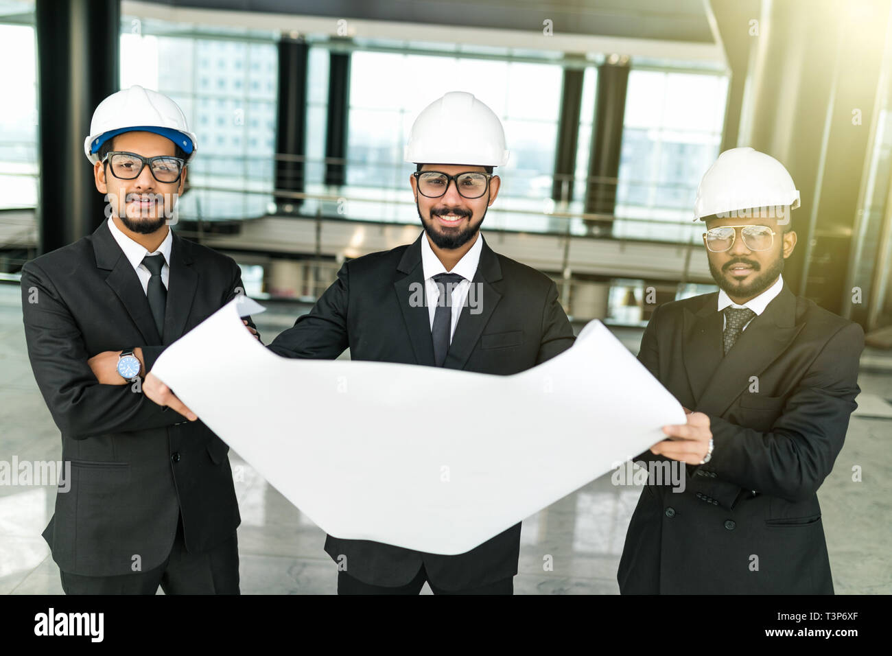 Qualified young architects are standing and discussing plan of building ...