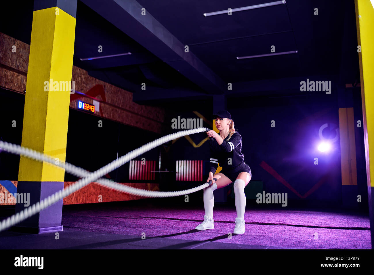 Fitness woman using training ropes for exercise at gym. Athlete working ...