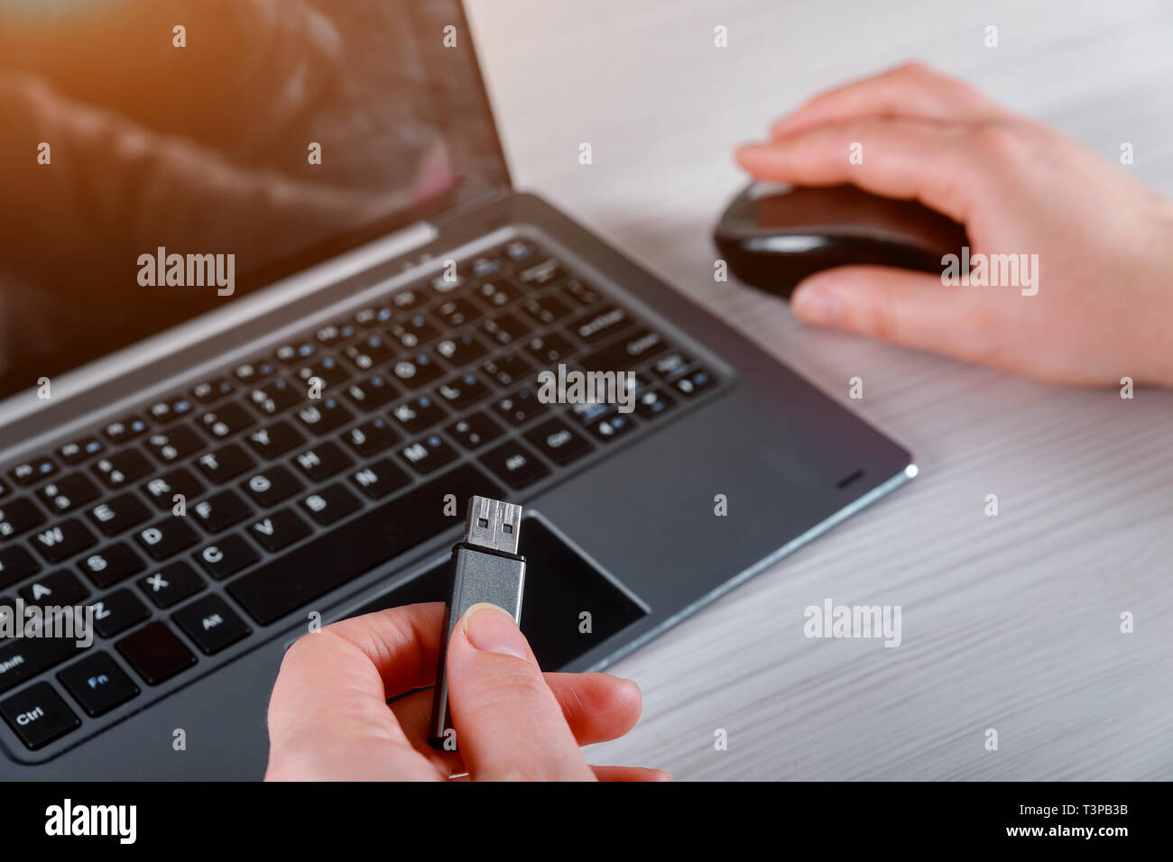 Hand of a woman holding a USB device connected to Laptop computer on ...
