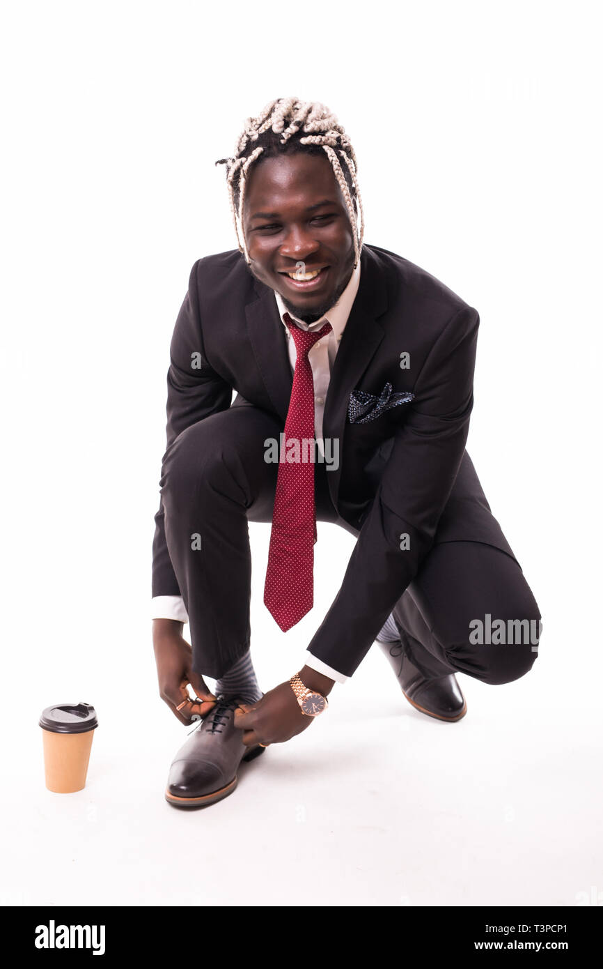 Crouching african businessman tying shoe laces looking at camera. Full ...