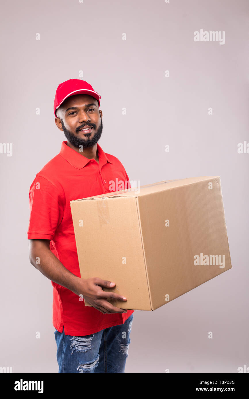 Side view of delivery man with box in studio. isolated gray background ...