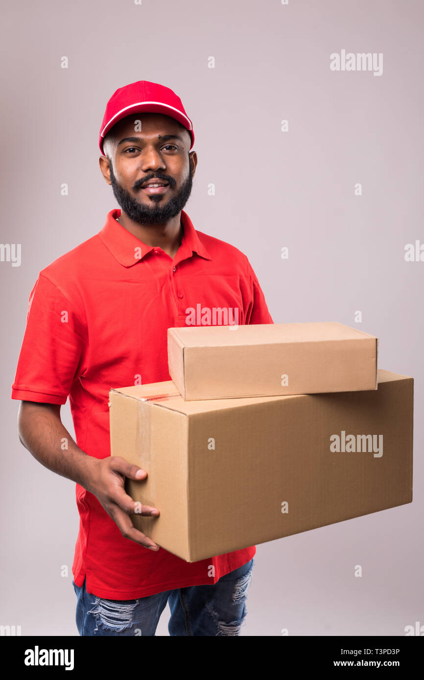 Side view of delivery man with box in studio. isolated gray background ...