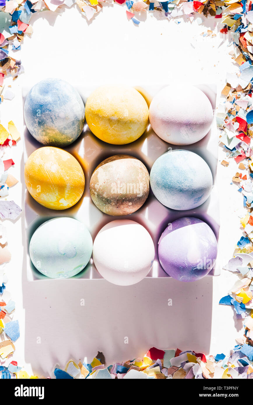 Colored eggs container with different colored egg, circled by pieces of ...