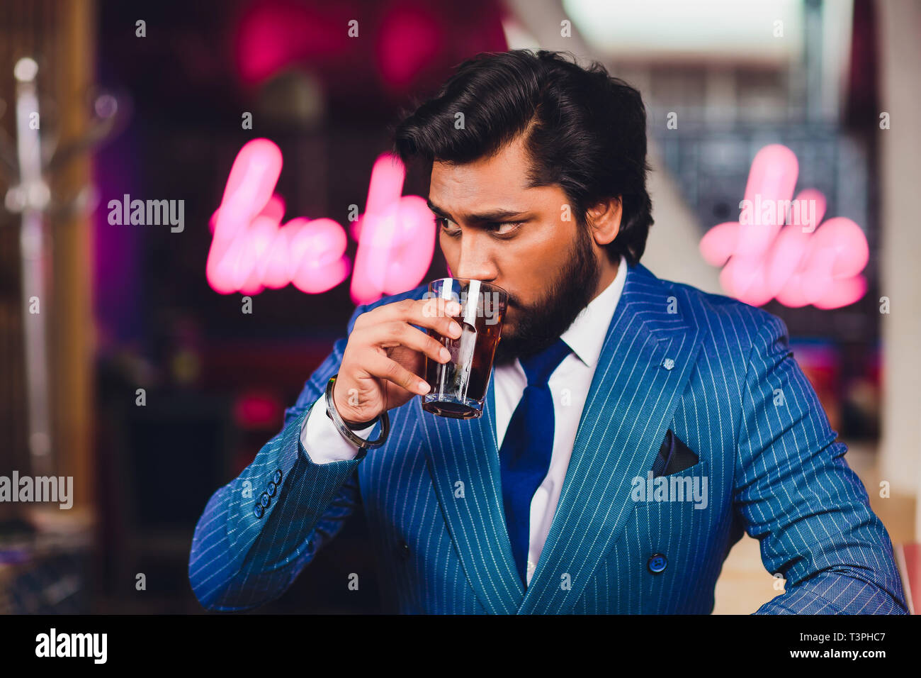 Handsome young man drinking cocktail at bar counter, wearing business ...