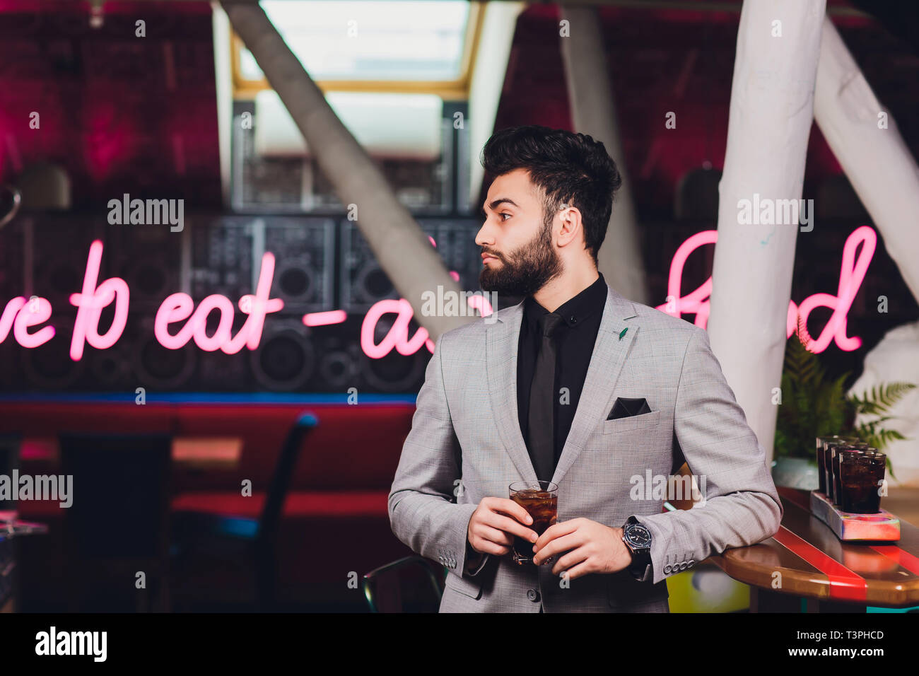 Handsome young man drinking cocktail at bar counter, wearing business ...