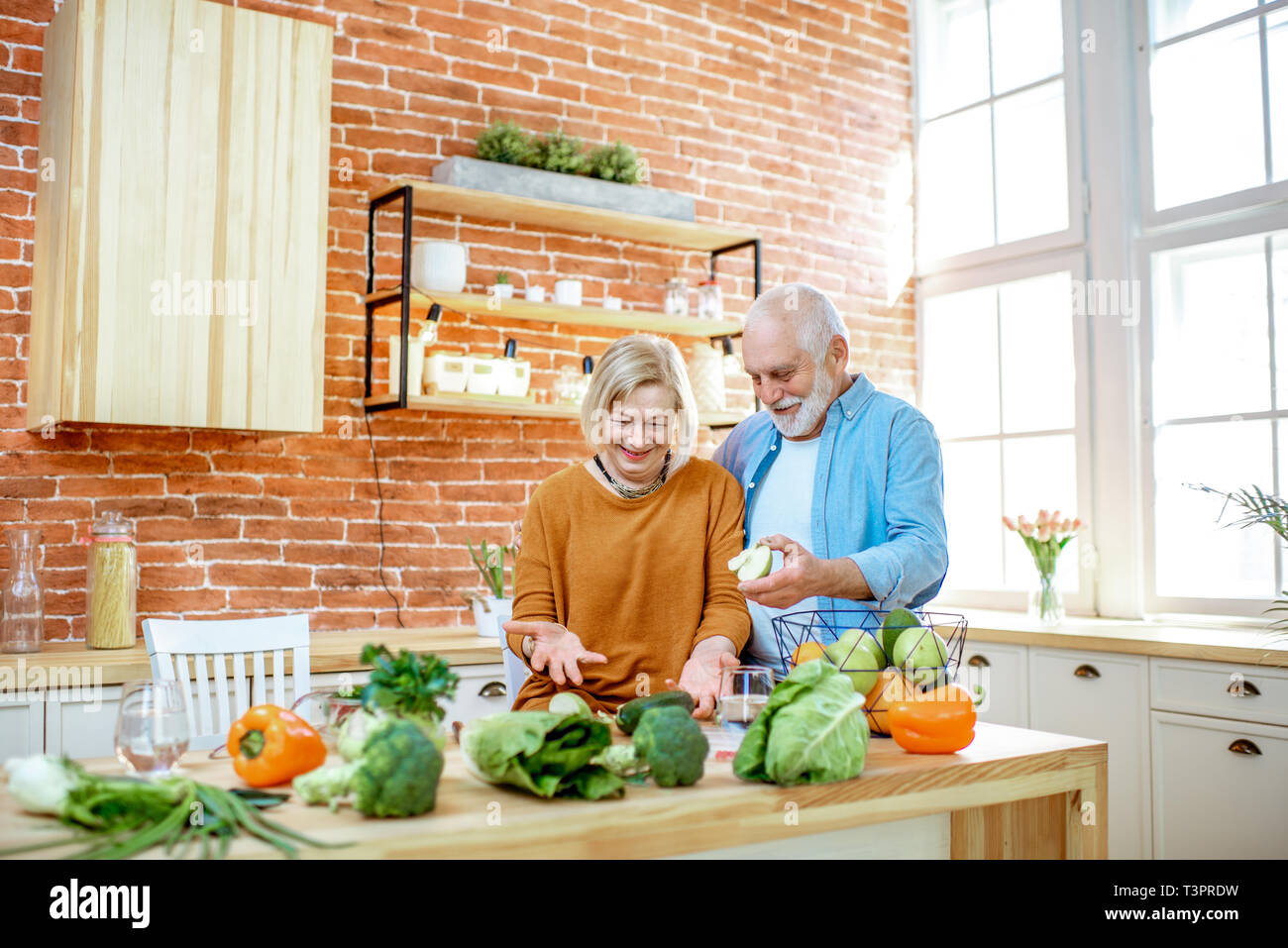 Cheerful senior couple eating fruits standing together with healthy ...