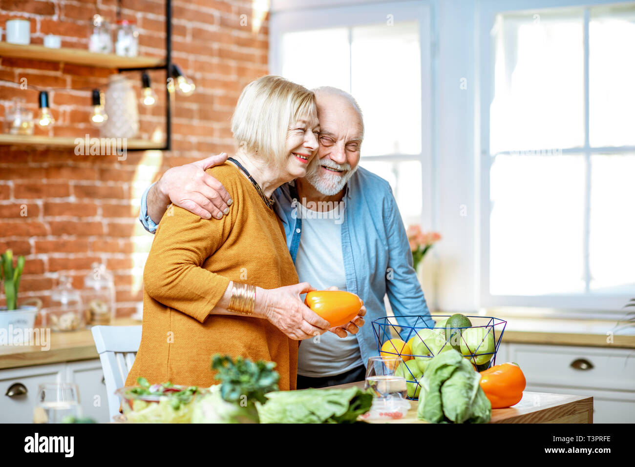 Cheerful senior couple cooking food with healthy fresh ingredients on ...