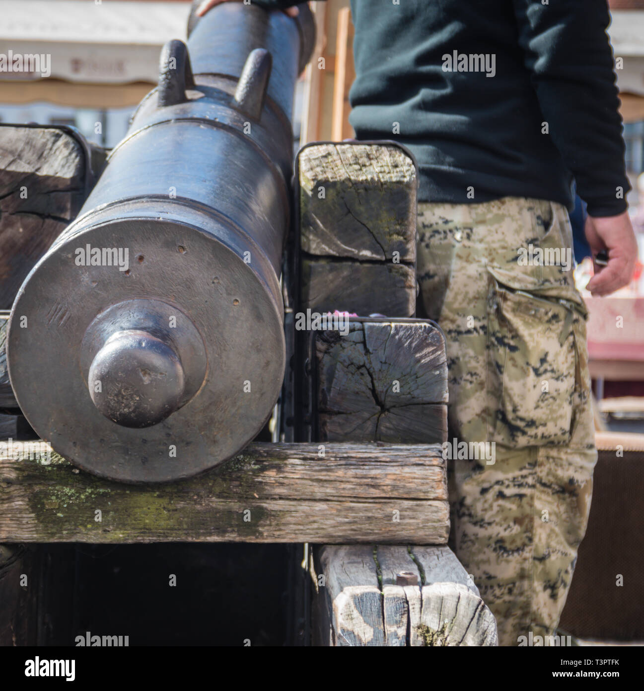 Man in camouflage holding old ball gunpowder canon Stock Photo - Alamy